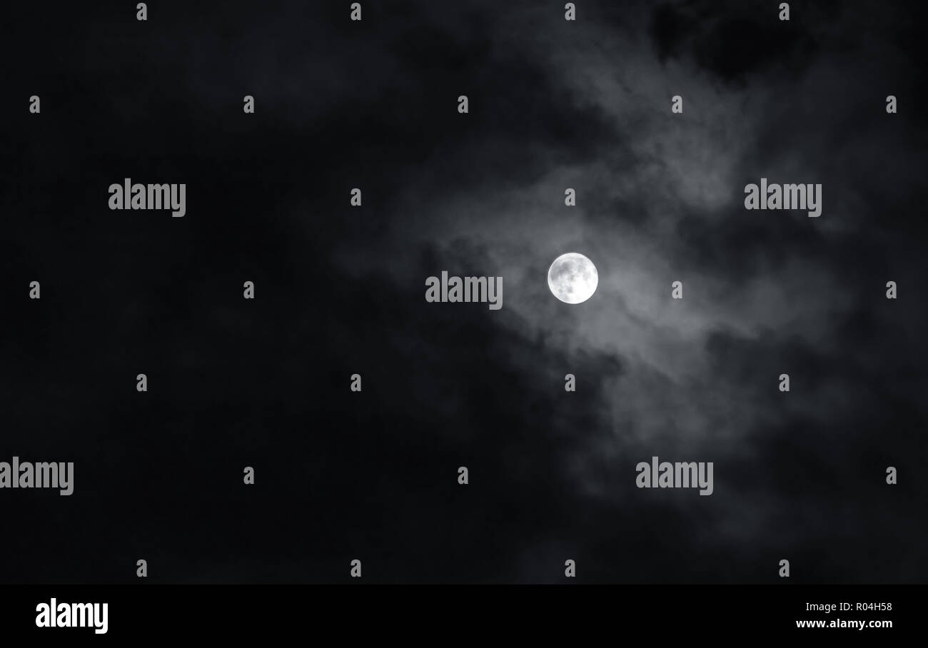 Full moon covered dark clouds in the night sky Stock Photo - Alamy