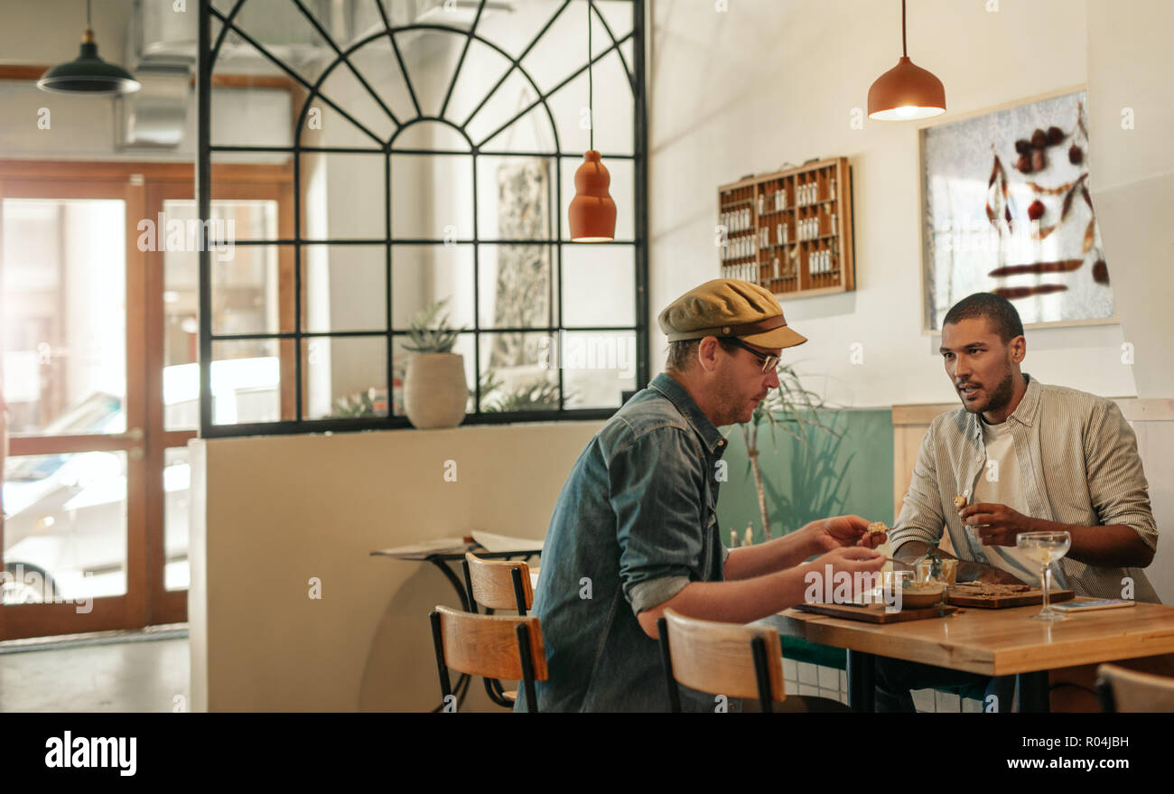 Friends talking over food and drinks in a bistro Stock Photo - Alamy