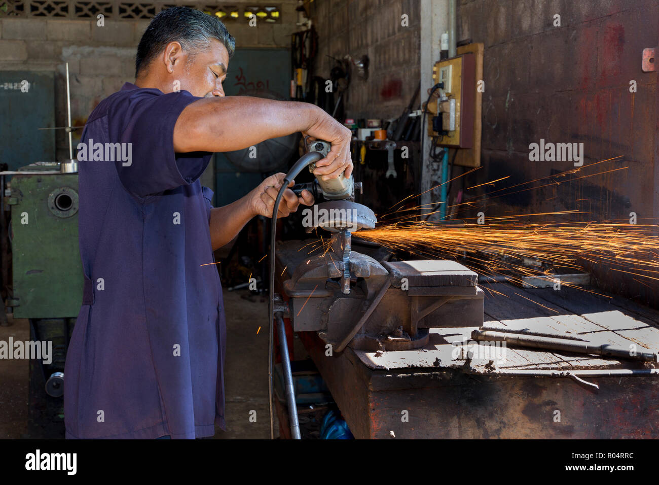 Thai worker sanding a metal part in his workshop Stock Photo - Alamy