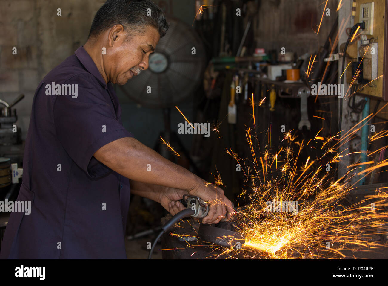 Thai worker sanding a metal part in his workshop Stock Photo - Alamy