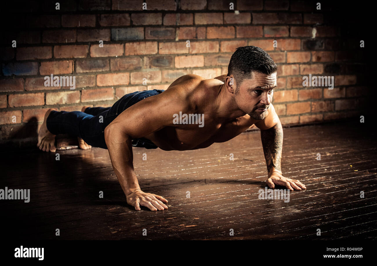 Muscular male engaged in cross fit training and performing push-ups ...