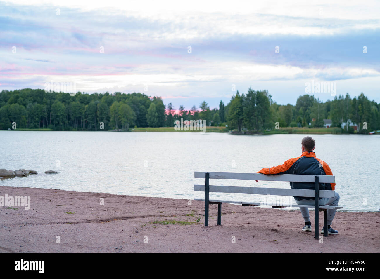 Young Man Sitting On The Bench By The Lake Stock Photo - Alamy
