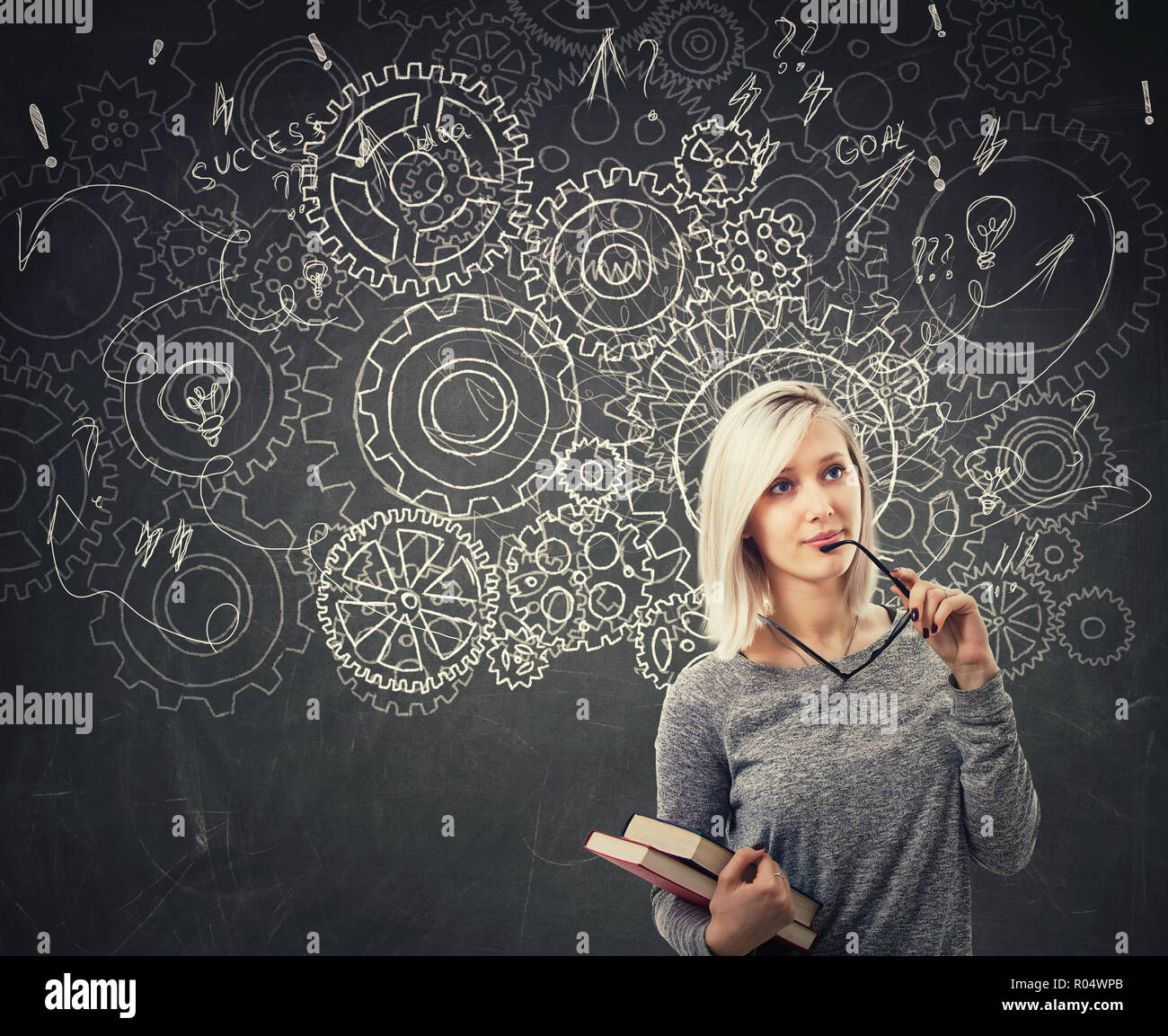 Hard thinking serious smart woman holding books over blackboard ...