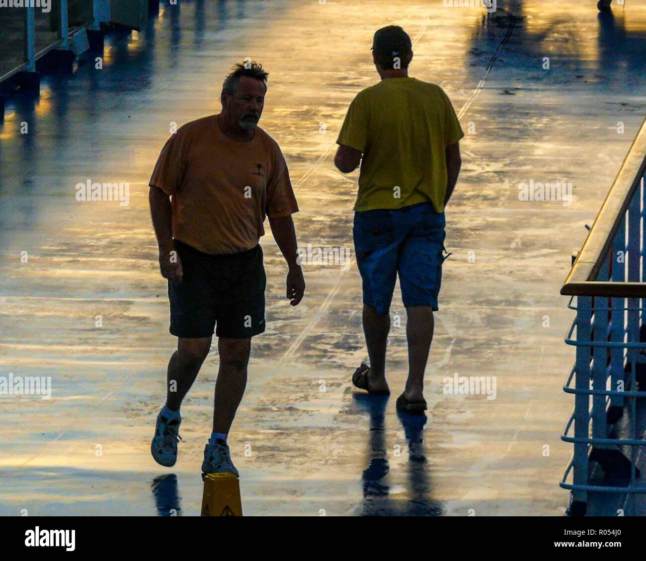 In early morning light on a Caribbean cruise, two male passengers pass ...