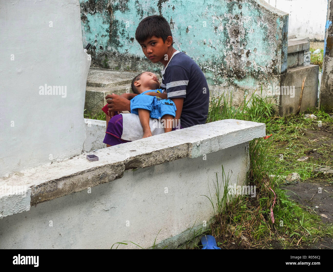 A young boy carrying his little brother while sleeping. He and his ...