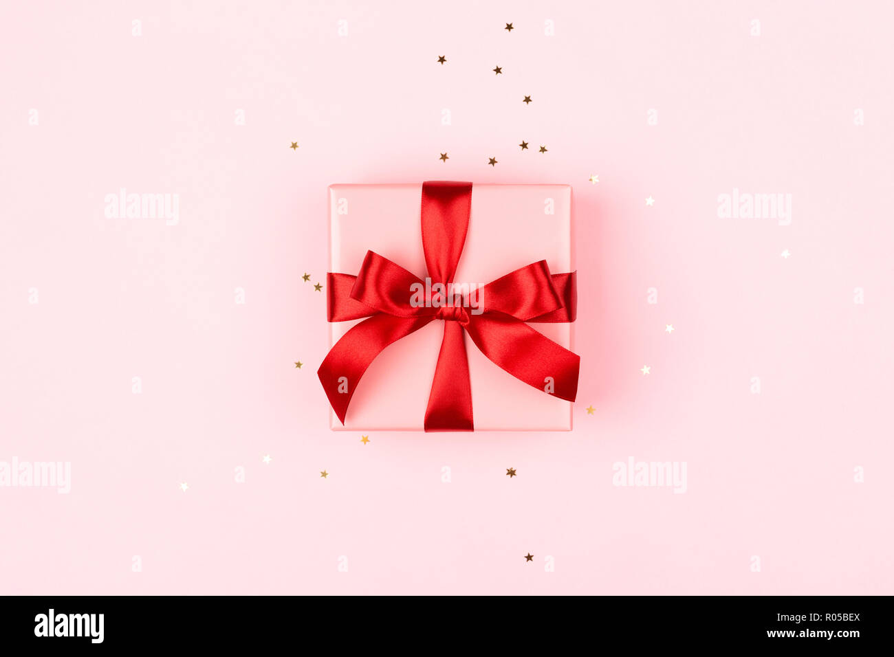 Pink gift box with red bow on the pink background with sparkles ...