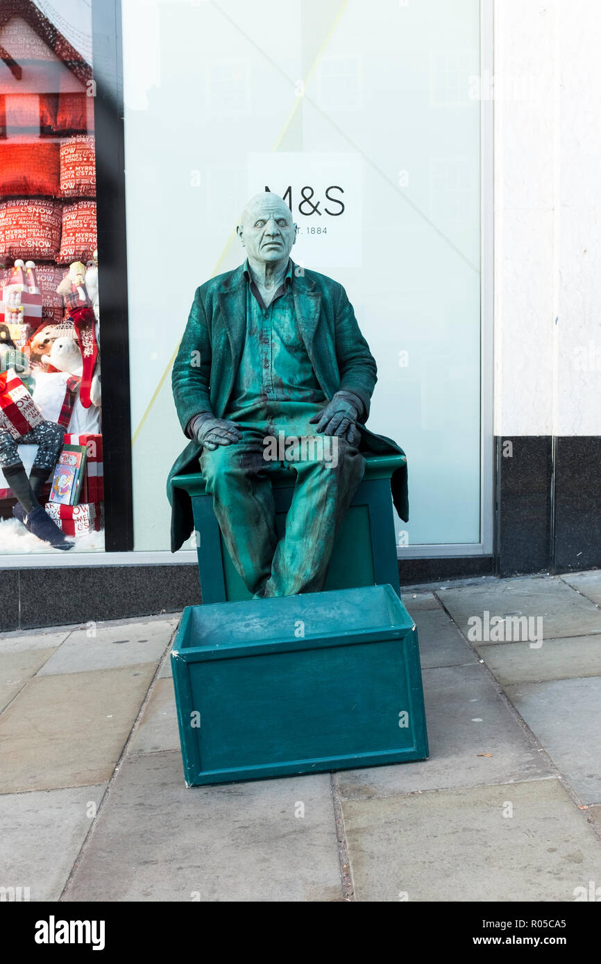 'Human statue' dressed all in green sits patiently awaiting a donation ...