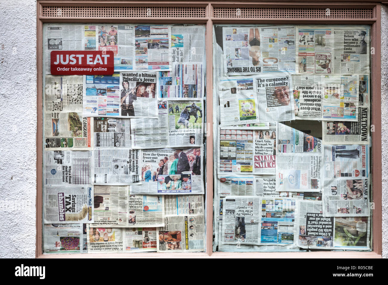 Shop window covered on the inside with newpaper pages Stock Photo - Alamy
