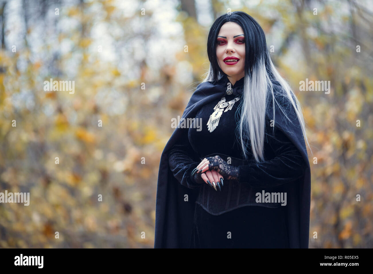 Photo of smiling female vampire in black cloak with amulet against ...
