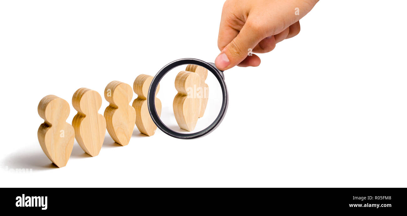 Magnifying glass is looking at the Wooden figures of people stand in ...