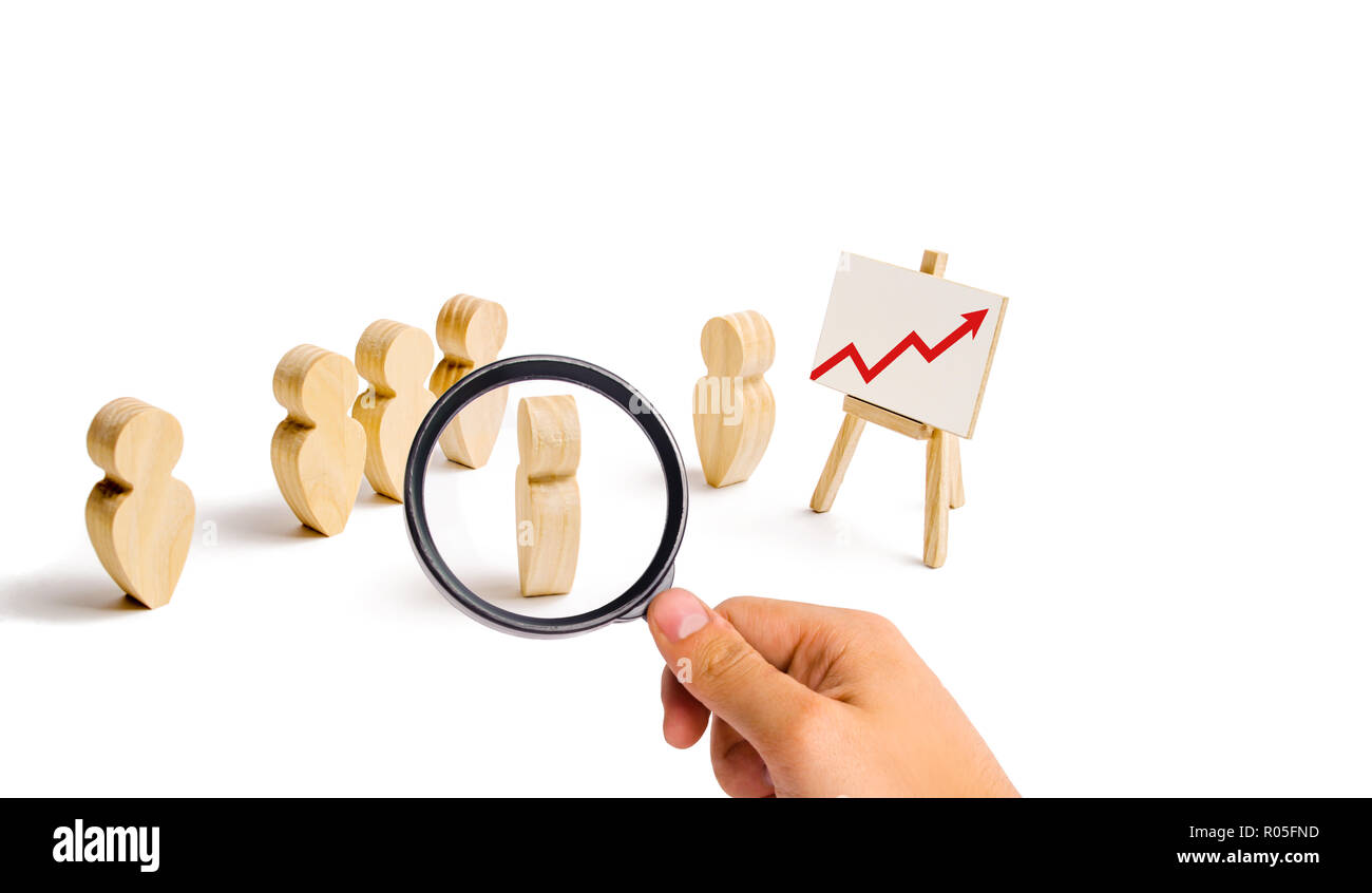 Magnifying glass is looking at the Wooden figures of people stand in ...