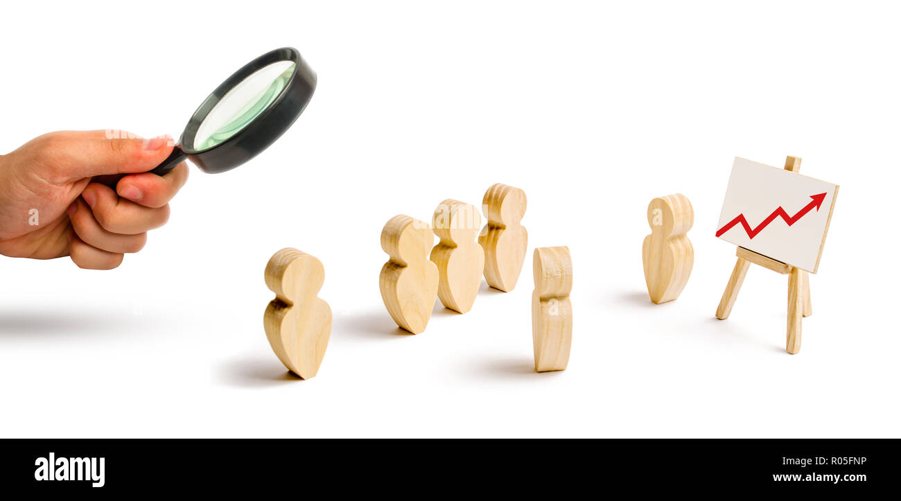 Magnifying glass is looking at the Wooden figures of people stand in ...