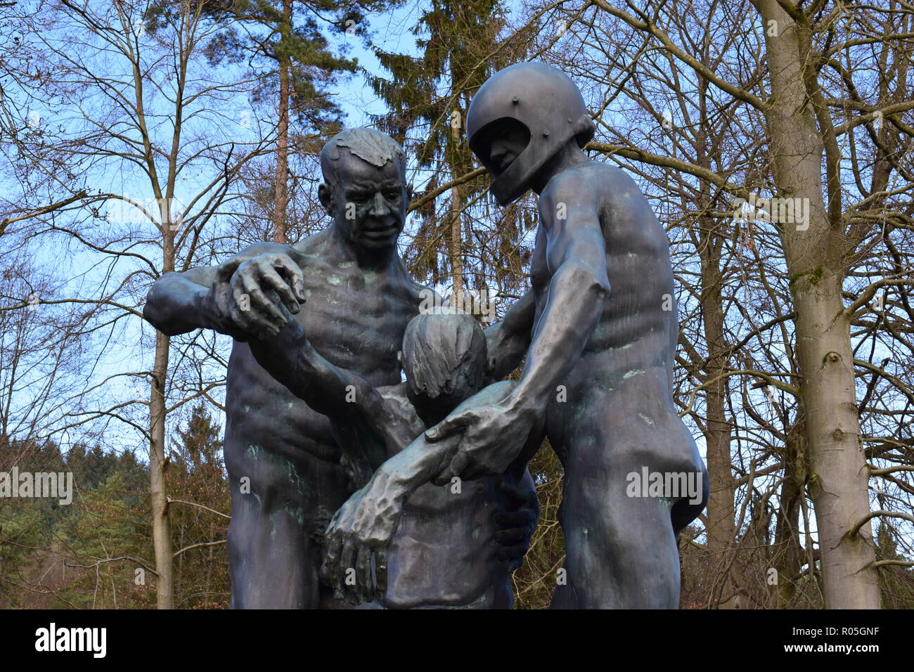 A bronze statue under blue sky during winter in a War Cemetery depicts ...