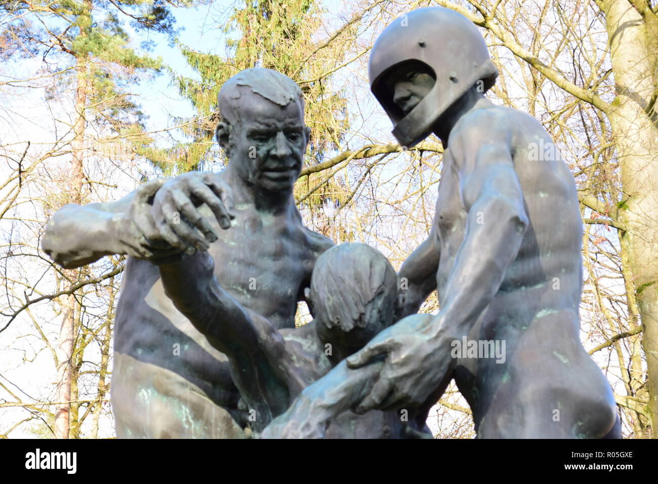 A bronze statue under blue sky during winter in a War Cemetery depicts ...