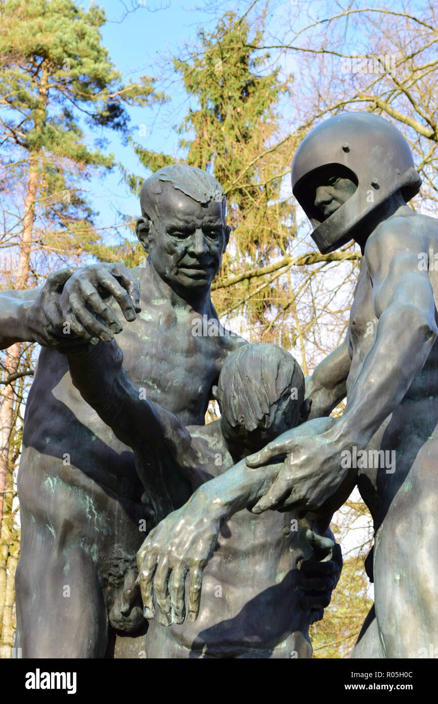 A bronze statue under blue sky during winter in a War Cemetery depicts ...