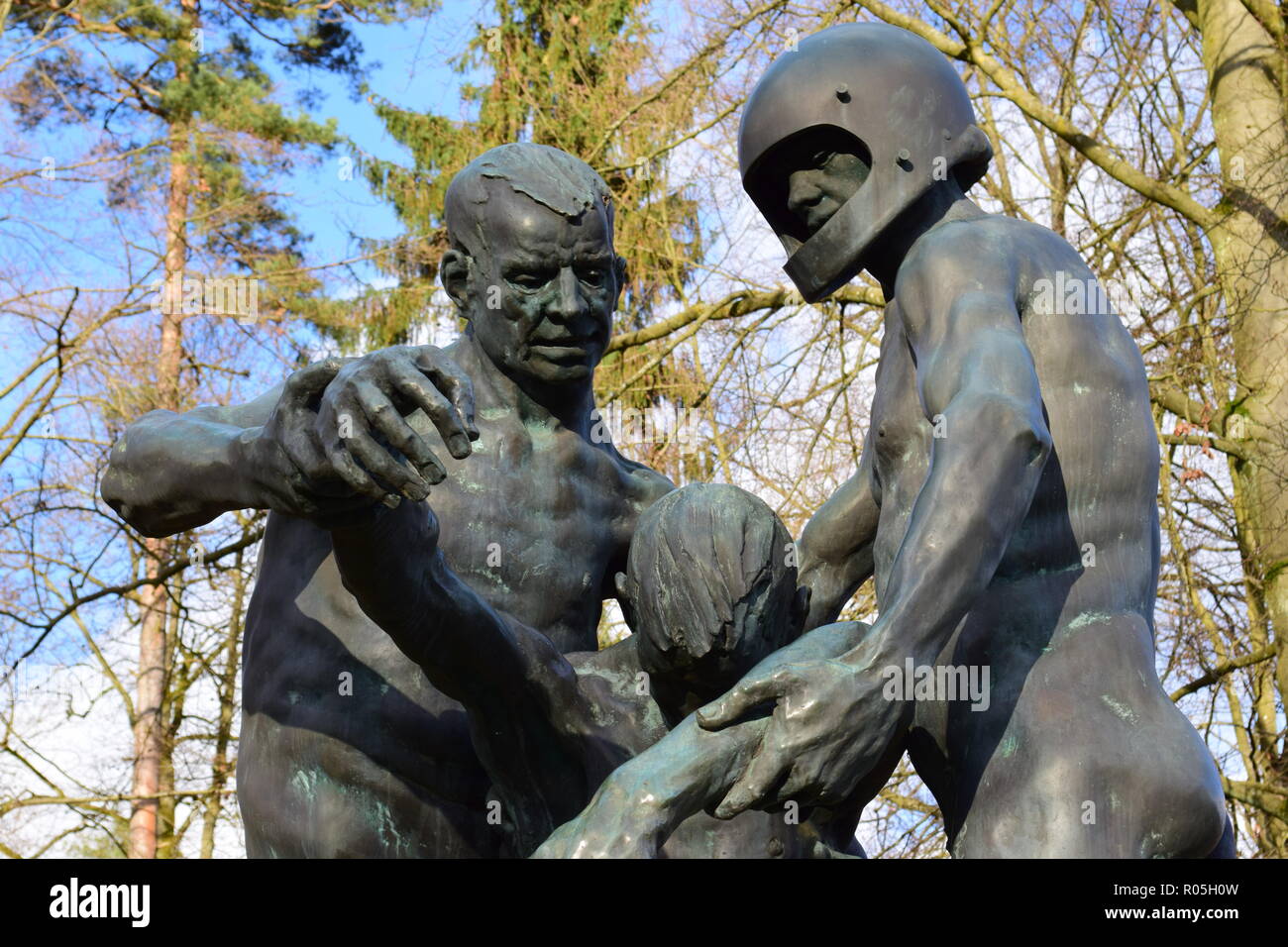 A bronze statue under blue sky during winter in a War Cemetery depicts ...