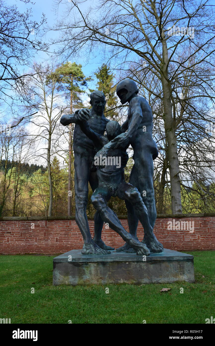 A bronze statue under blue sky during winter in a War Cemetery depicts ...