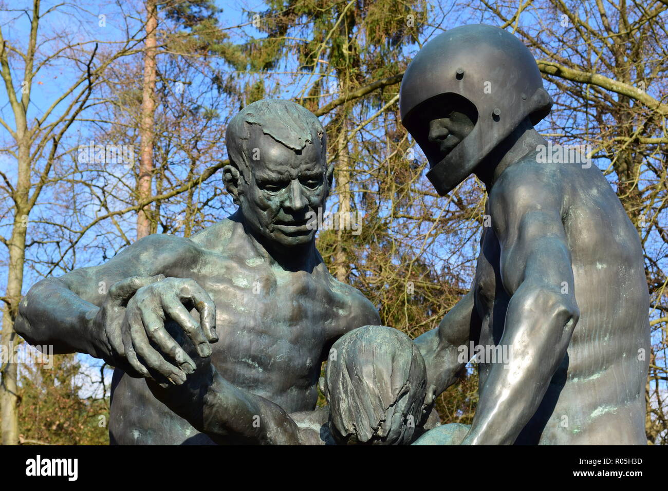 A bronze statue under blue sky during winter in a War Cemetery depicts ...