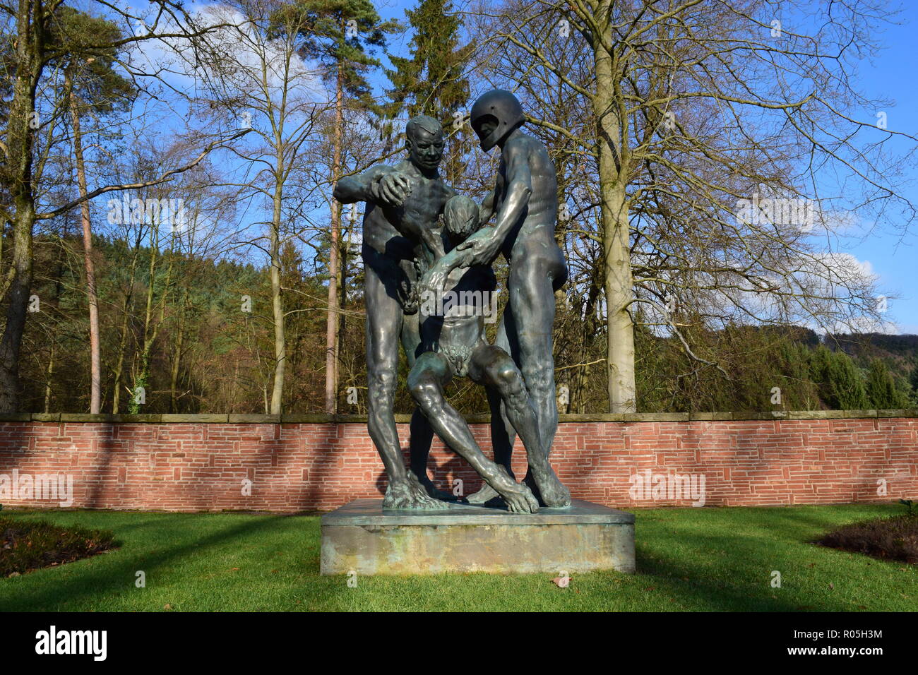 A bronze statue under blue sky during winter in a War Cemetery depicts ...