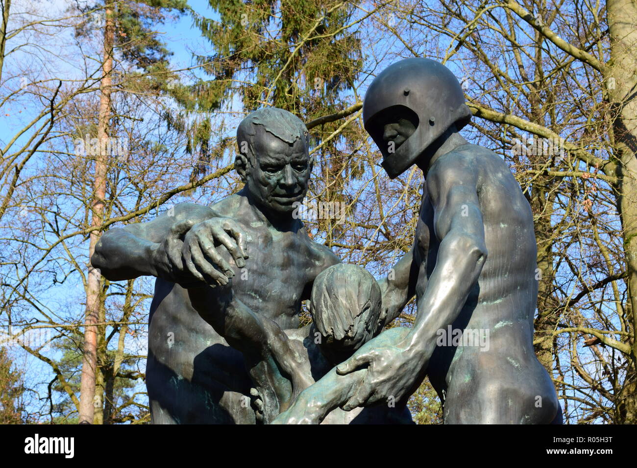 A bronze statue under blue sky during winter in a War Cemetery depicts ...
