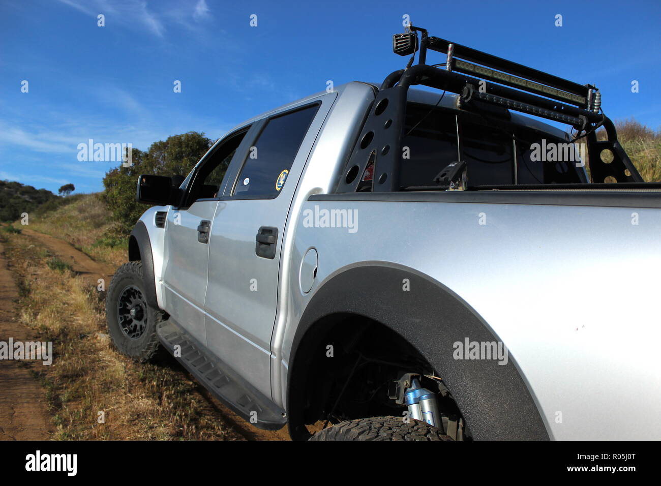 Silver and black customized Ford F150 Raptor SVT climbing a hill on ...