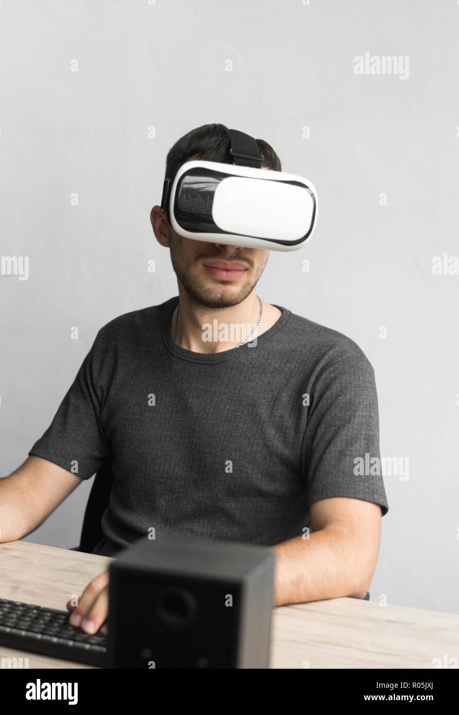 Young man wearing virtual reality goggles headset, vr box and sitting ...