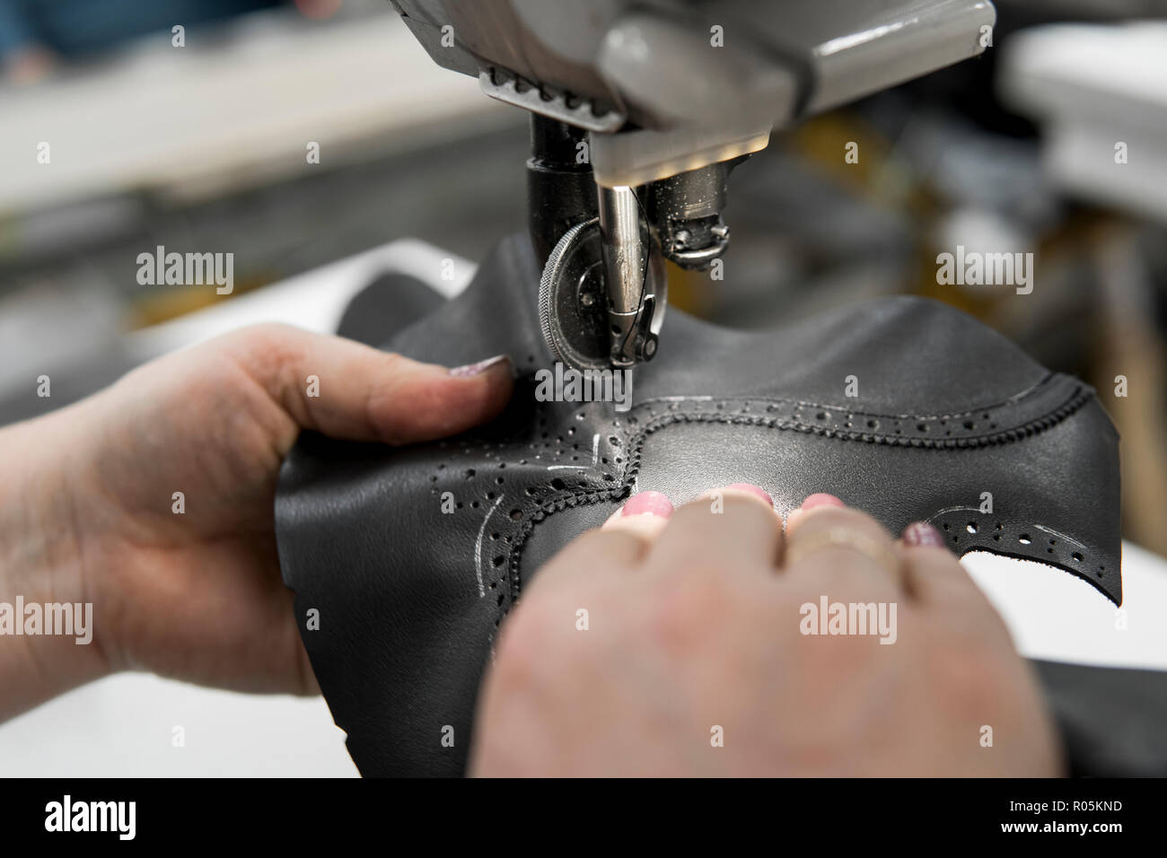 Sewing machine in a leather workshop in action with hands working on a ...