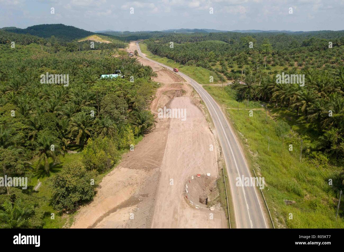 Rural road under construction across palm oil plantation . The road is ...