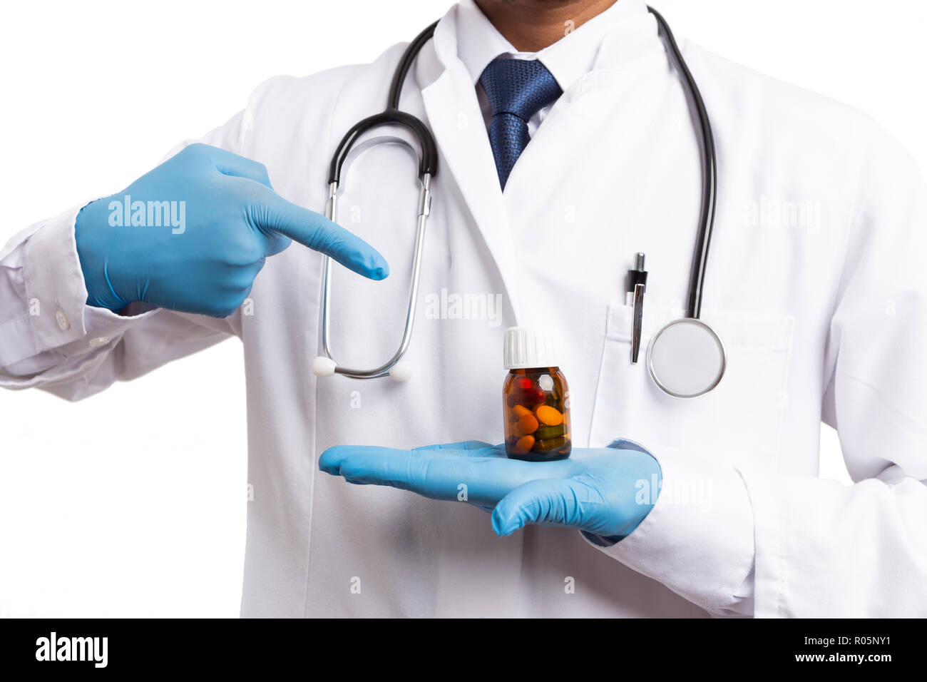 Indian medic wearing blue gloves pointing at pill bottle with index ...