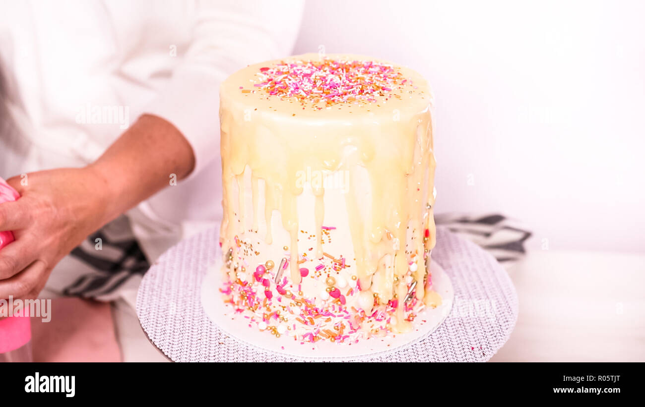 Step by step. Piping pink italian buttercream icing on top of a tall ...