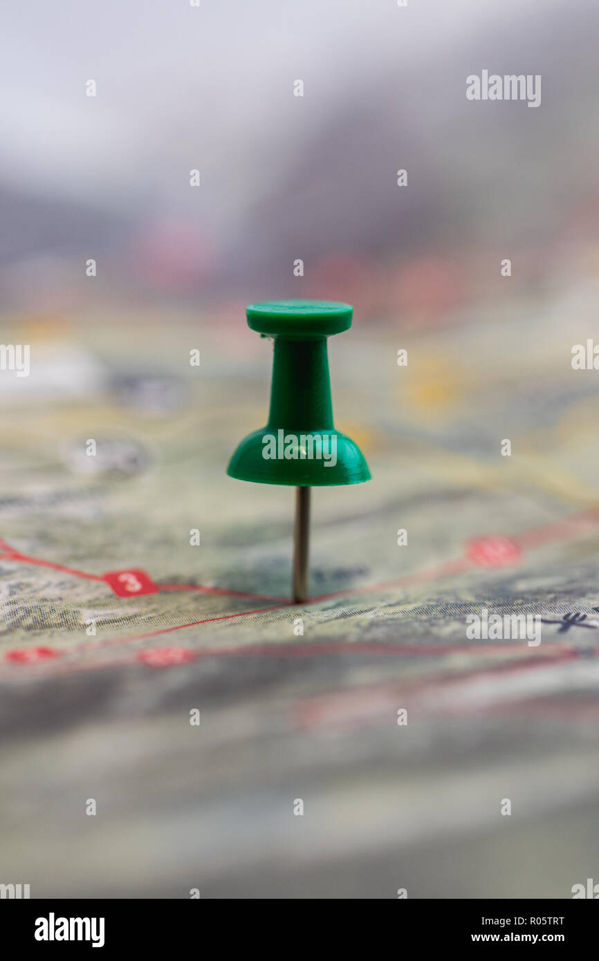 macro of green pin marks a location of a destination on a map ...