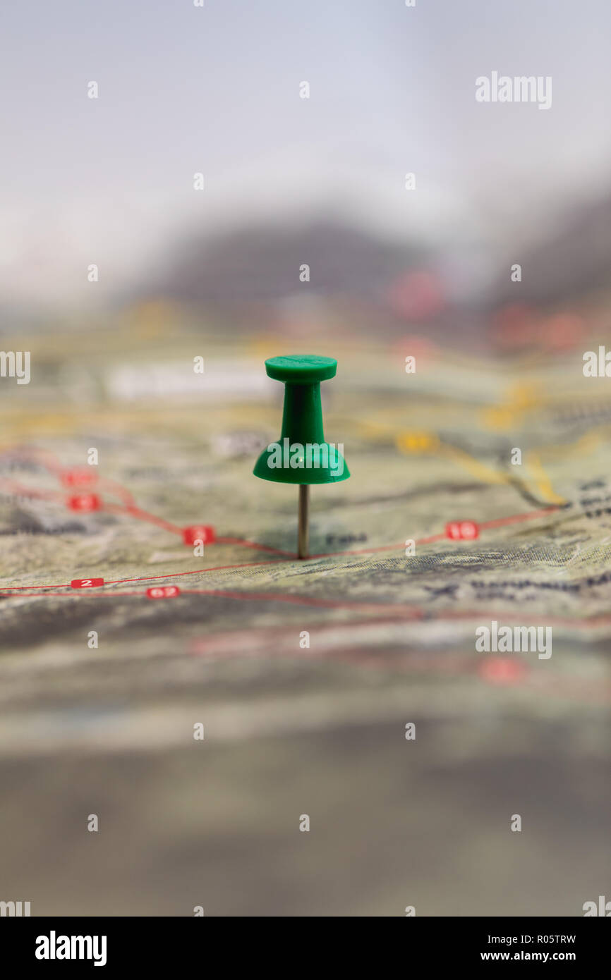 macro of green pin marks a location of a destination on a map ...