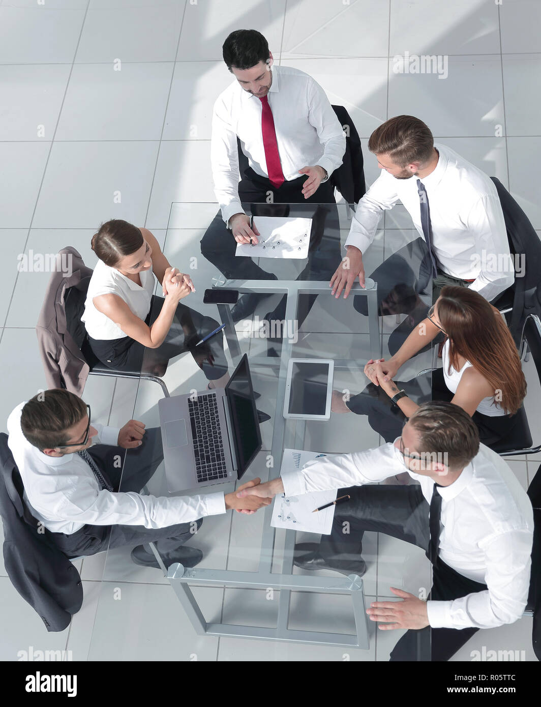 Office workers gather around a table to do research and implement new ...