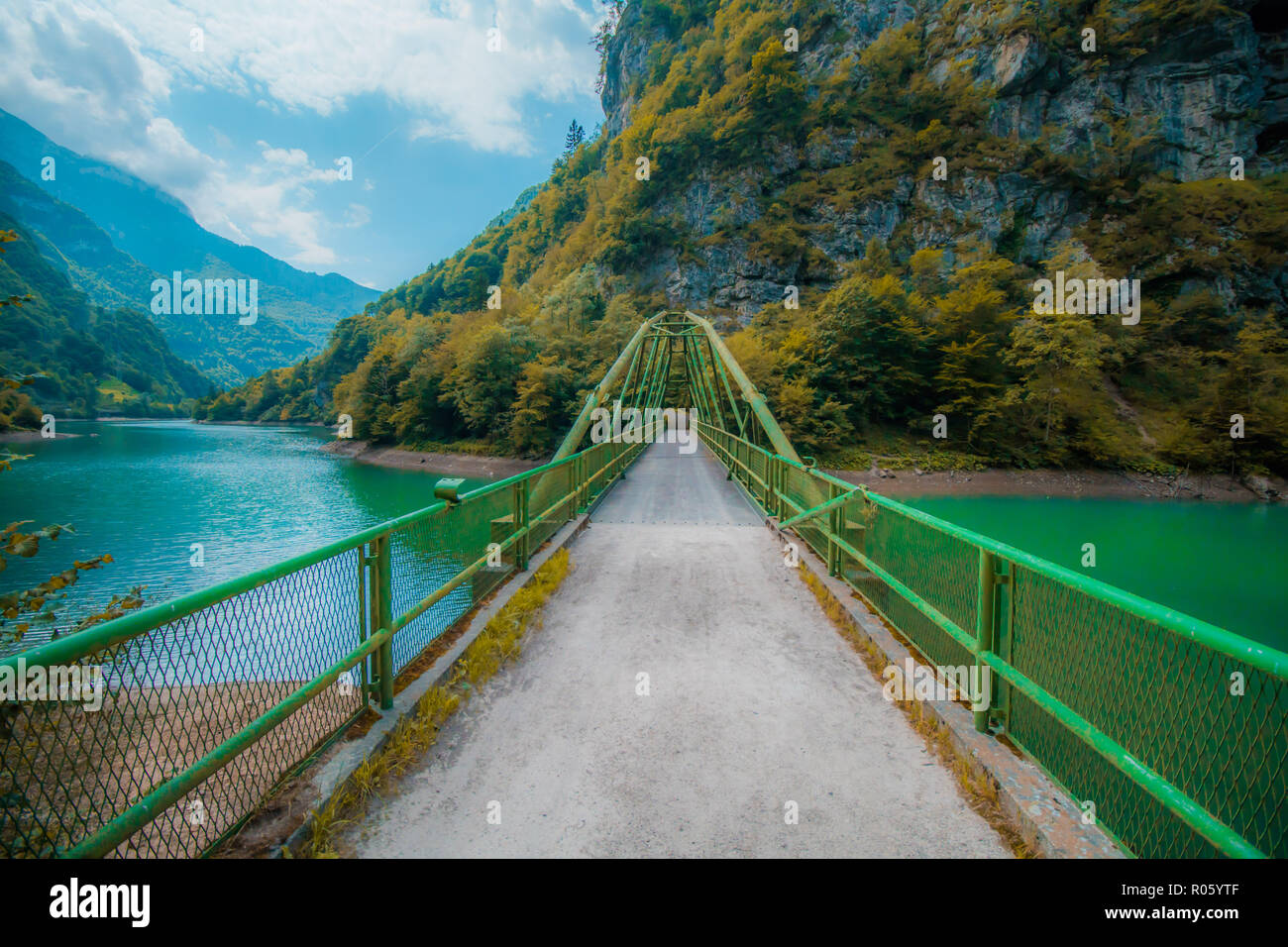 Green steel bridge in the middle of the mountains on the river in the ...