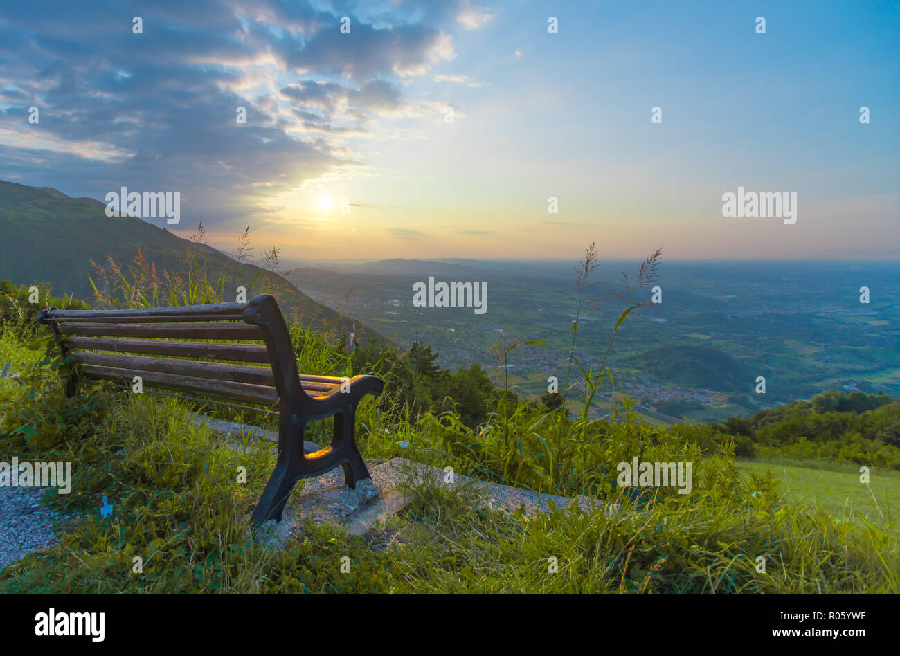 A bench in front of the beautiful sunrise on the hills covered with ...