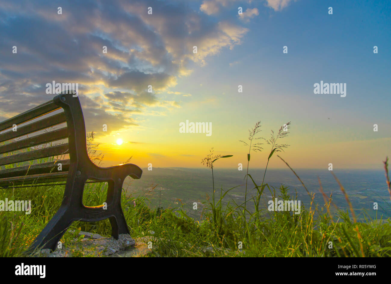 A bench in front of the beautiful sunrise on the hills covered with ...