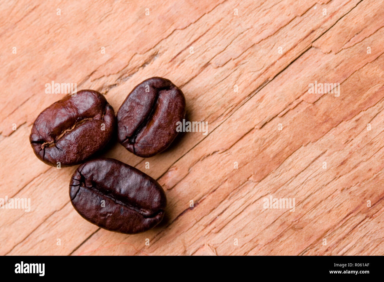three fried coffee beans closeup on wooden background Stock Photo - Alamy