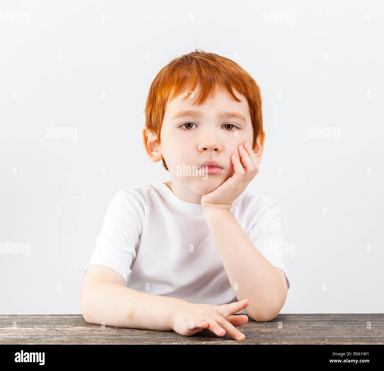 a portrait of a boy who holds his head with his hand over his chin ...