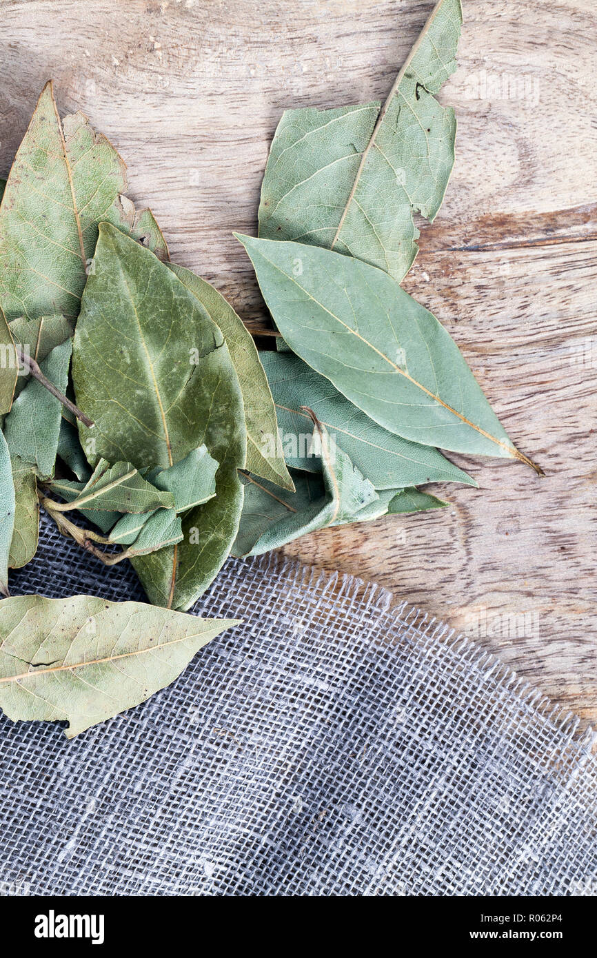 green dry leaves of bay leaf spice on a wooden board Stock Photo - Alamy