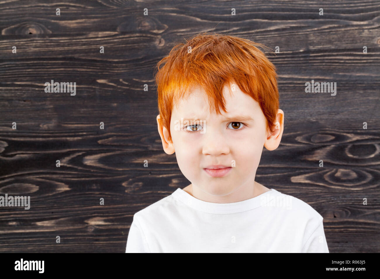 red-haired five year old child with an evil face expression against the ...