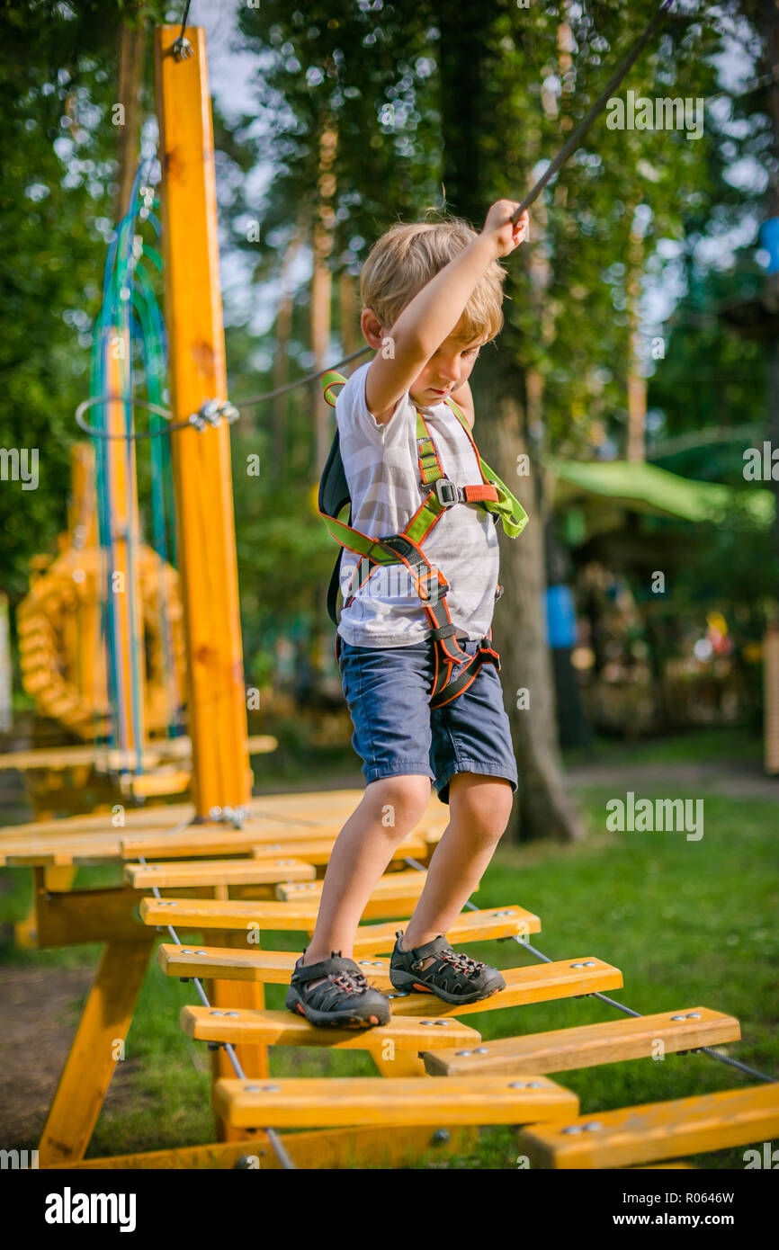 Boy climbing pass obstacles in rope park, fun activity Stock Photo - Alamy