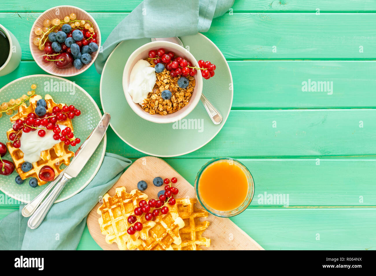 Breakfast with waffles, wipped cream, berries and granola, bright ...
