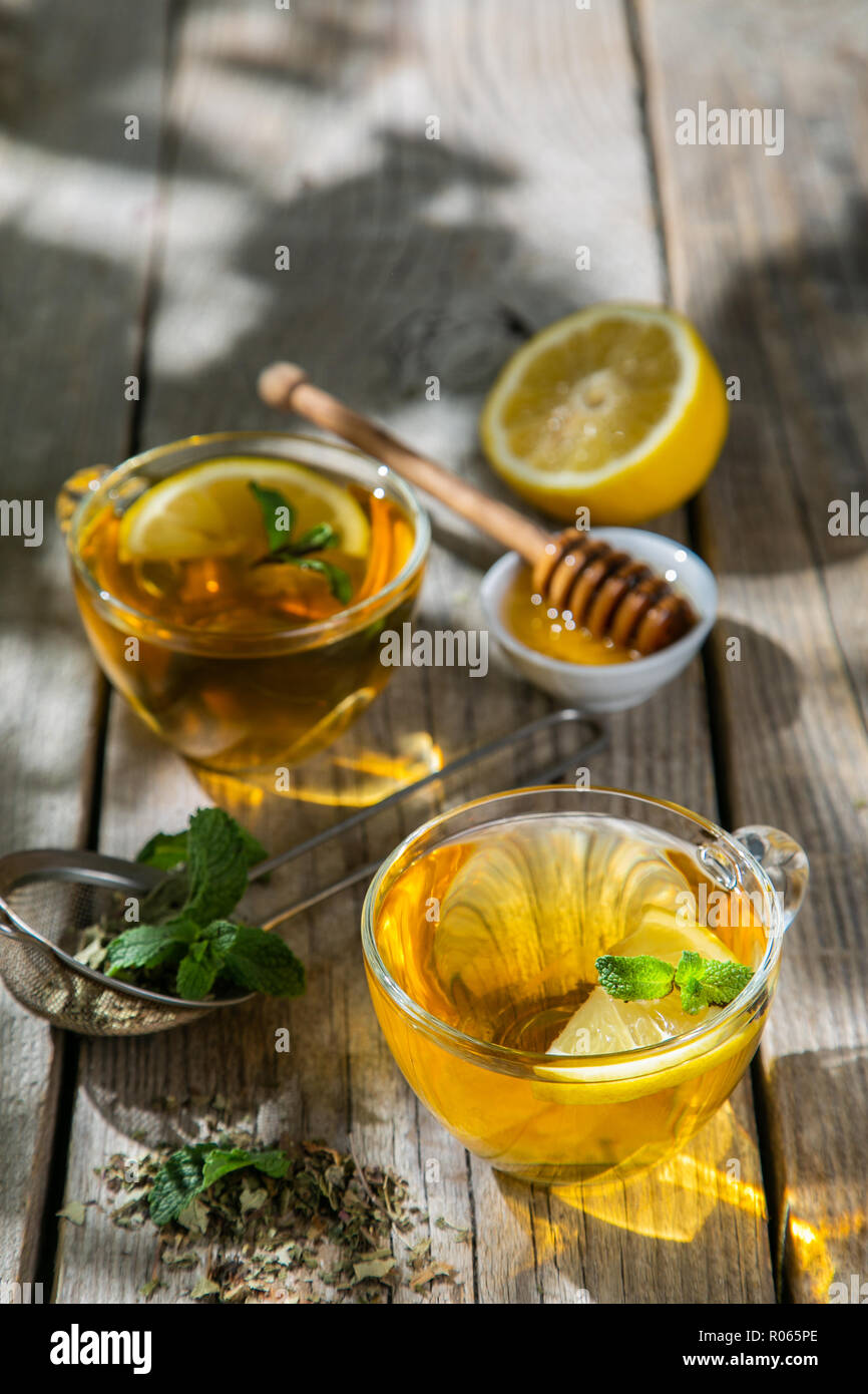Summer tea - tea cups on rustic wood background with leaves shades ...