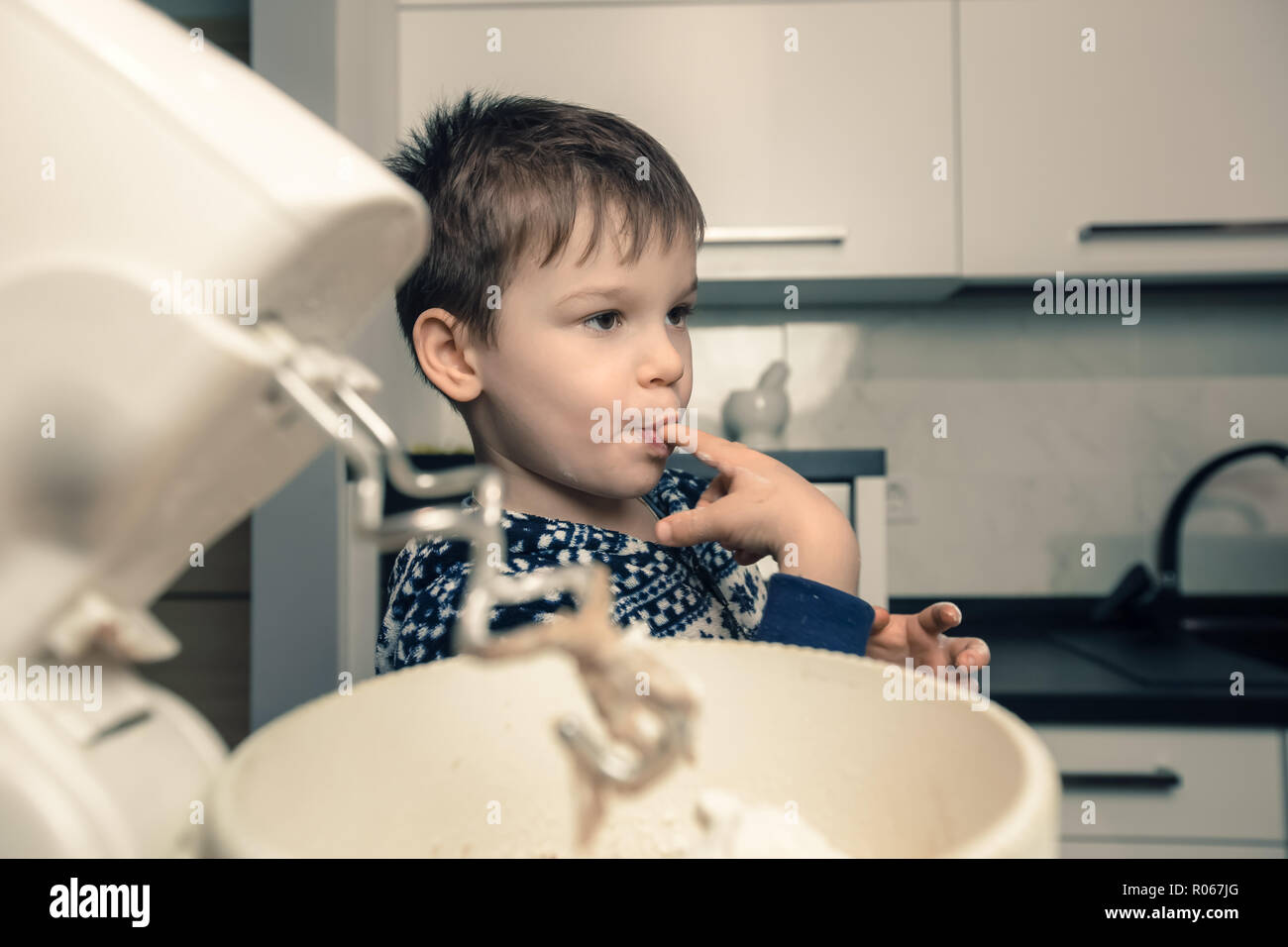 Happy Child cooking in the kitchen. Little boy helping mother to ...