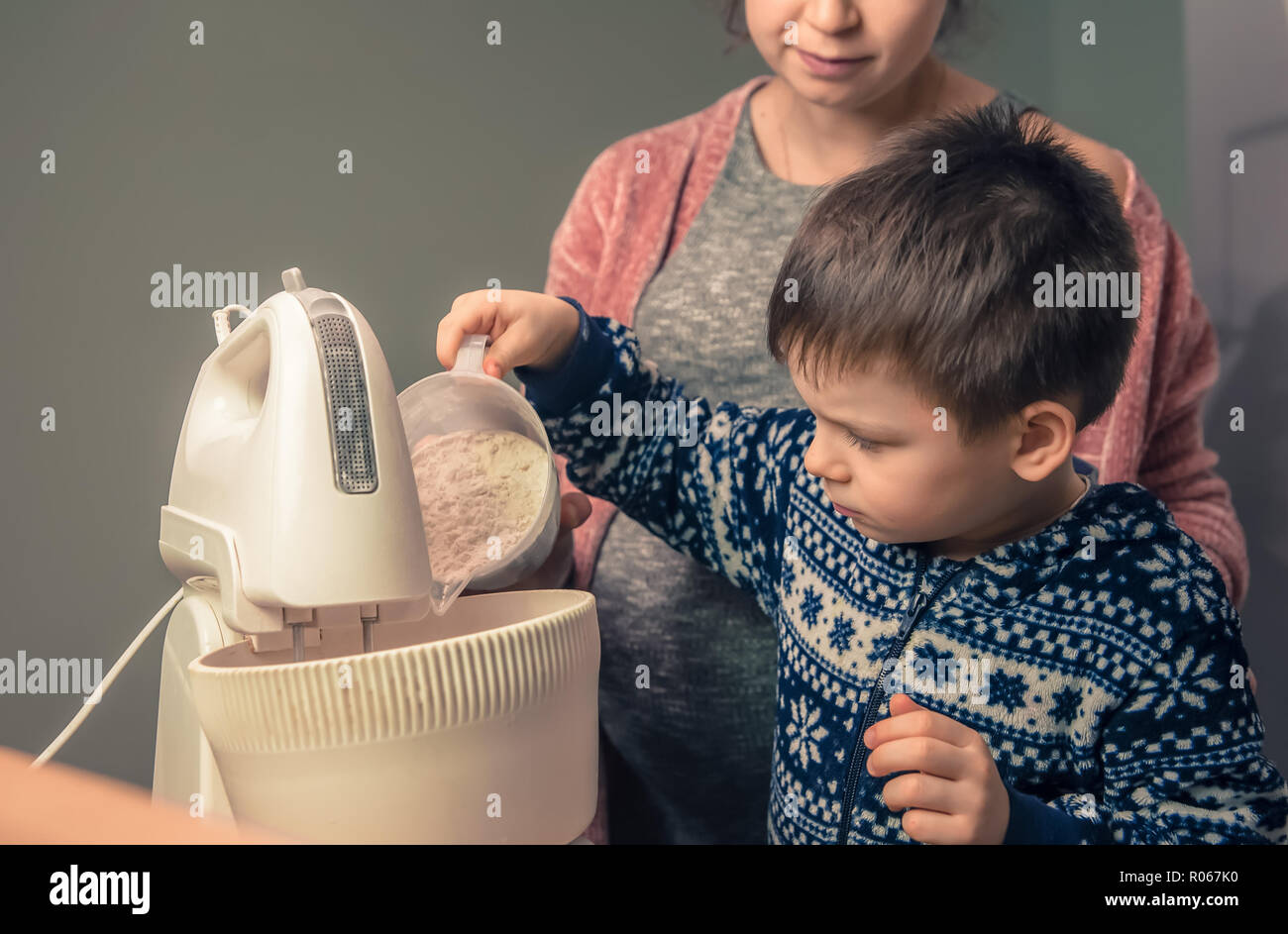Happy Child cooking in the kitchen. Little boy helping mother to ...