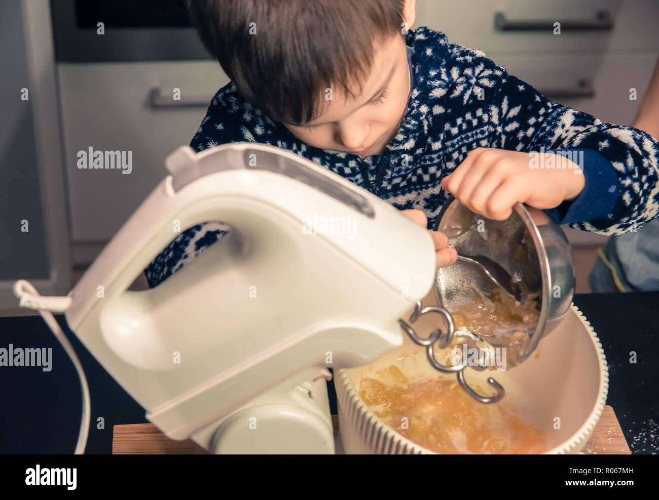 Happy Child cooking in the kitchen. Little boy helping mother to ...