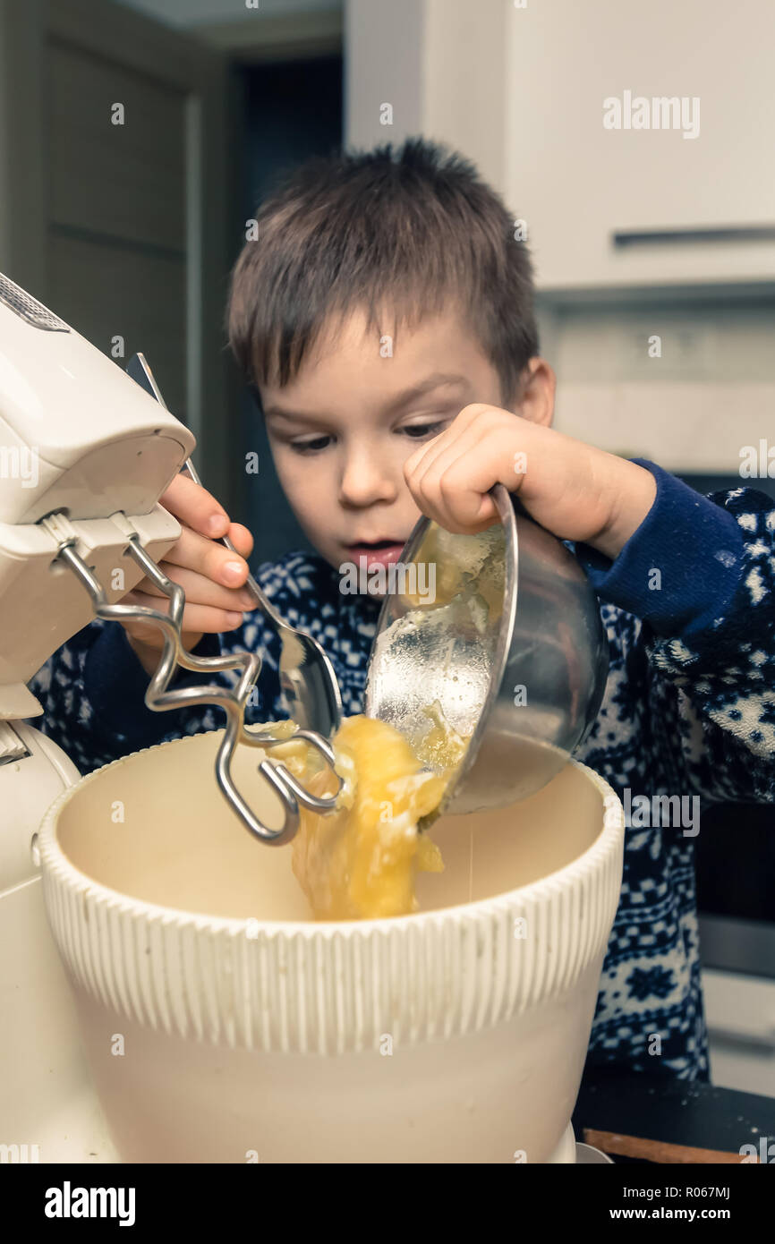 Happy Child cooking in the kitchen. Little boy helping mother to ...