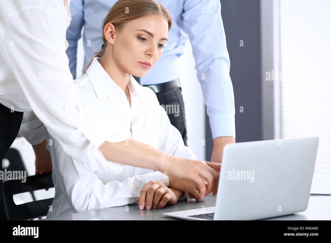 Group of business people using laptop computer while standing in office ...
