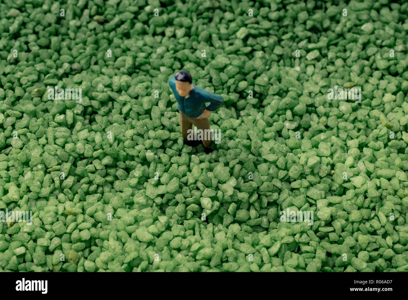 Tiny figurine of man miniature in green sand texture Stock Photo - Alamy