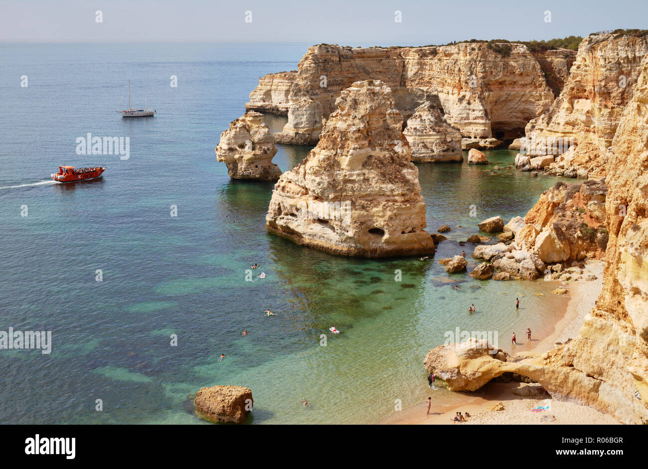 At the Algarve coast. Many brownstone rocks. A boat is approaching the ...